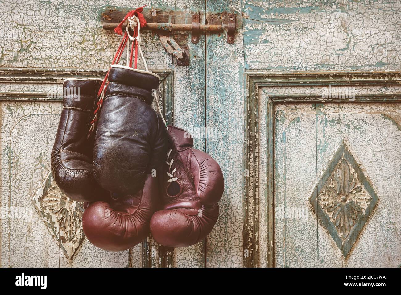 Two pair of vintage boxing gloves hanging on a weathered ancient wooden ...