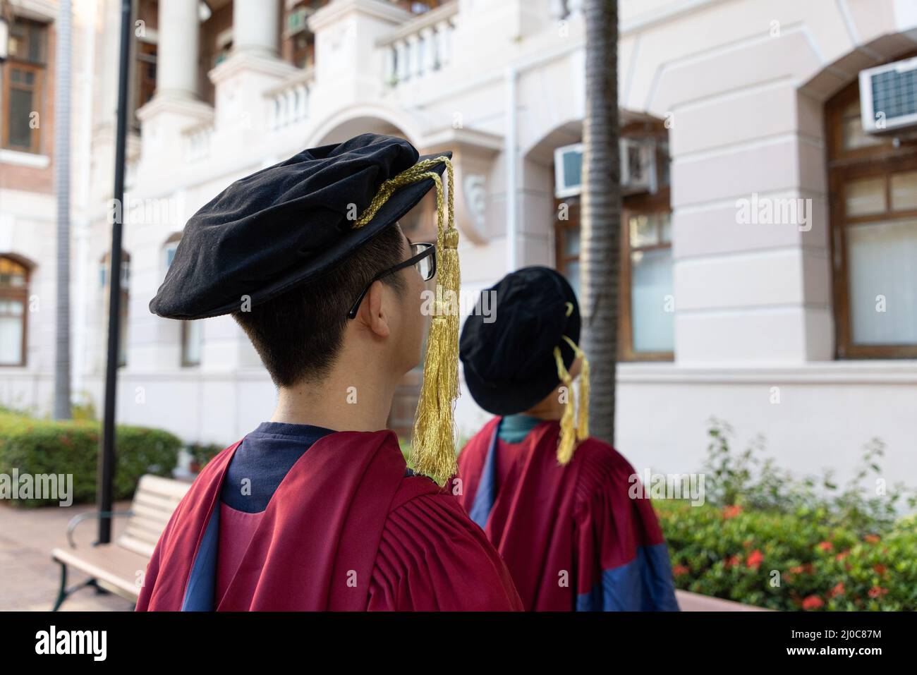 two happy proud PhD graduated male students in Academic dress gown ...
