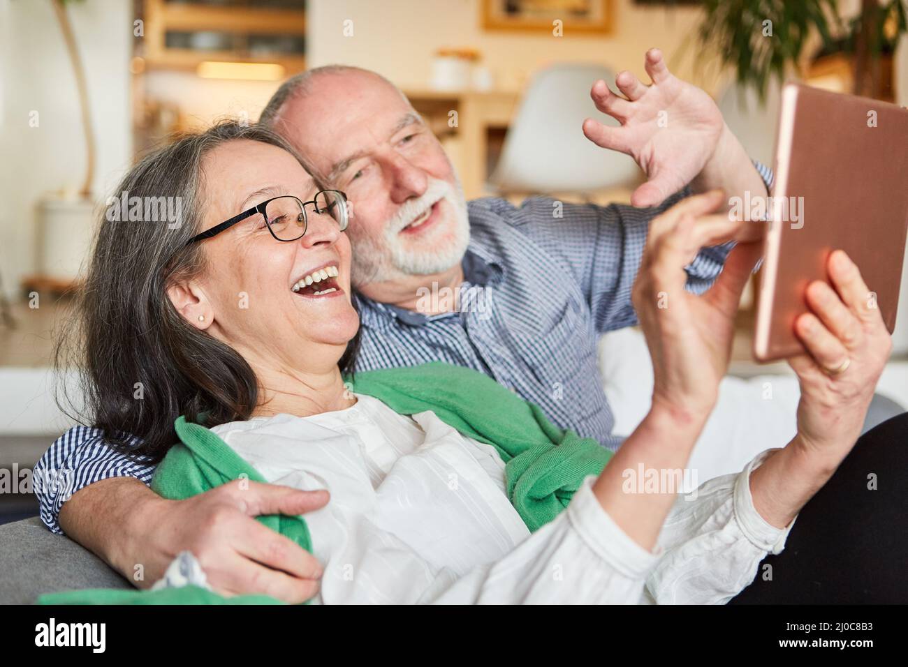 Happy senior couple video chatting with family on tablet computer at ...