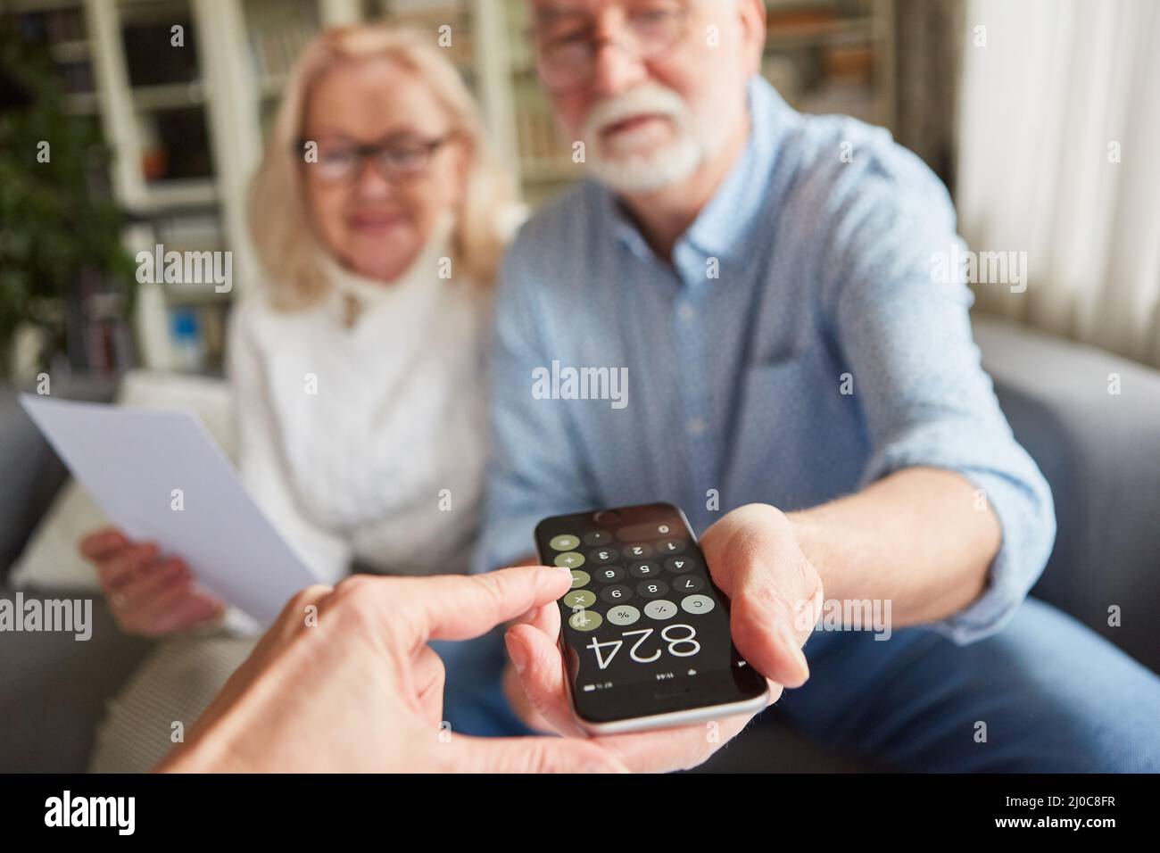 Senior couple and consultant using calculator to calculate cost of long ...