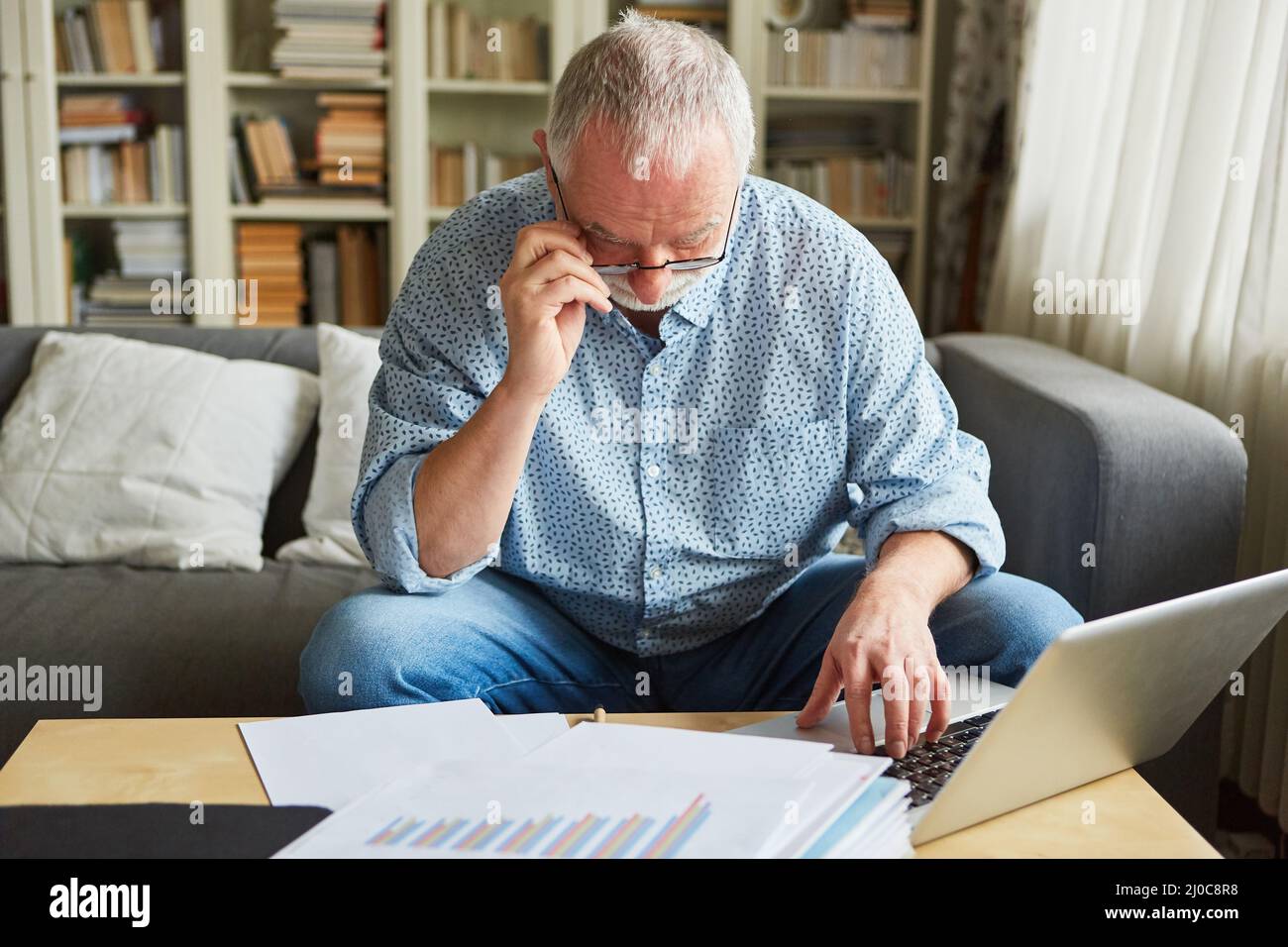 Old man at the laptop computer doing the bookkeeping or preparing the ...