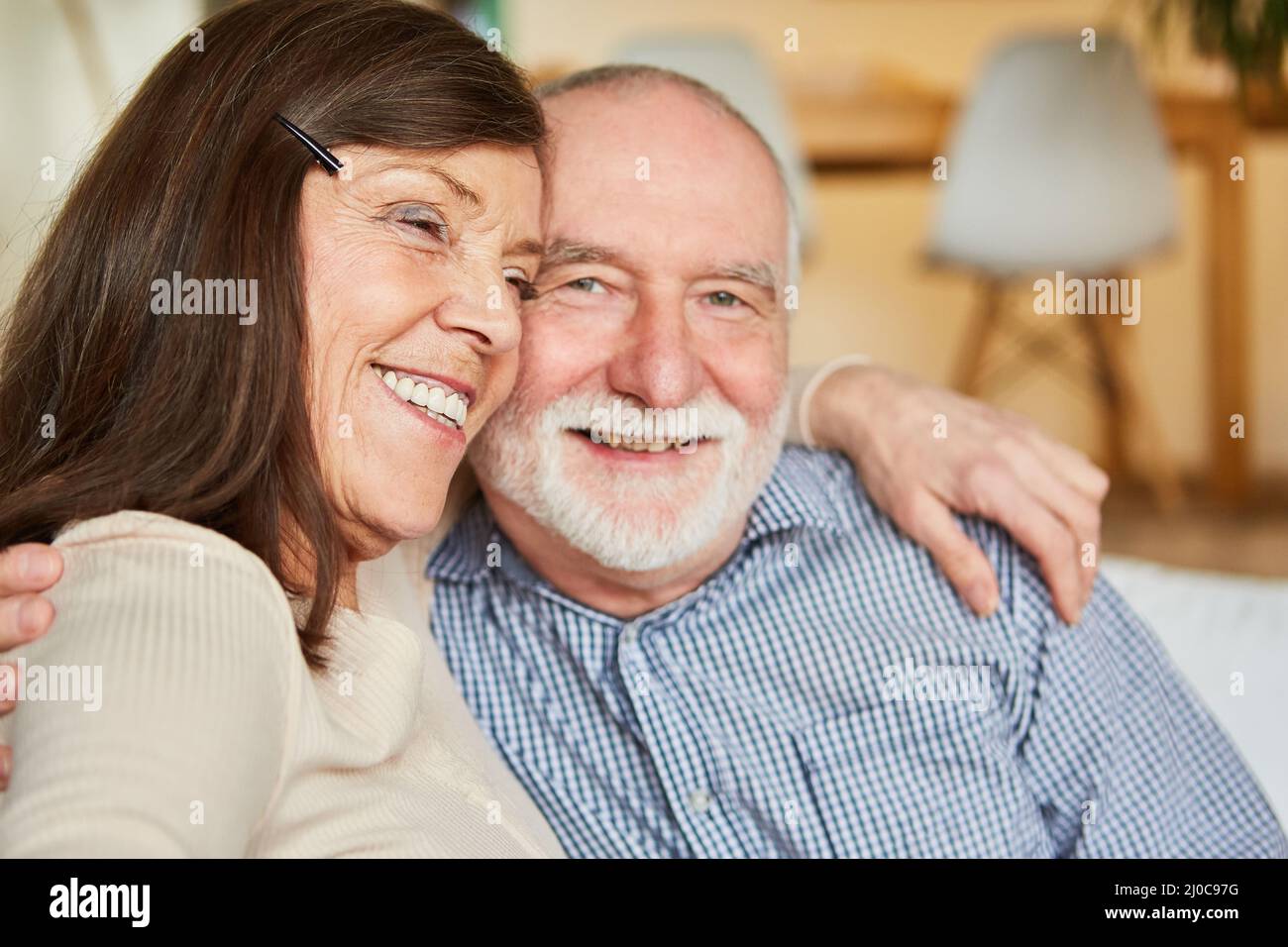 Senior Couple In Love Sitting Hugging On The Sofa As A Concept For Love