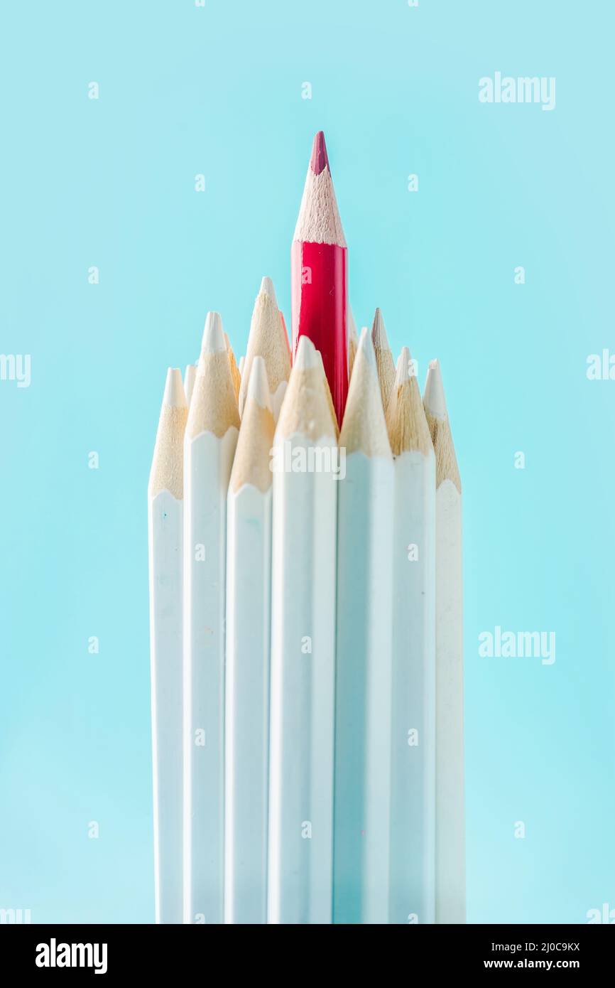 Business concept - lot of white pencils and one color pencil on blue ...