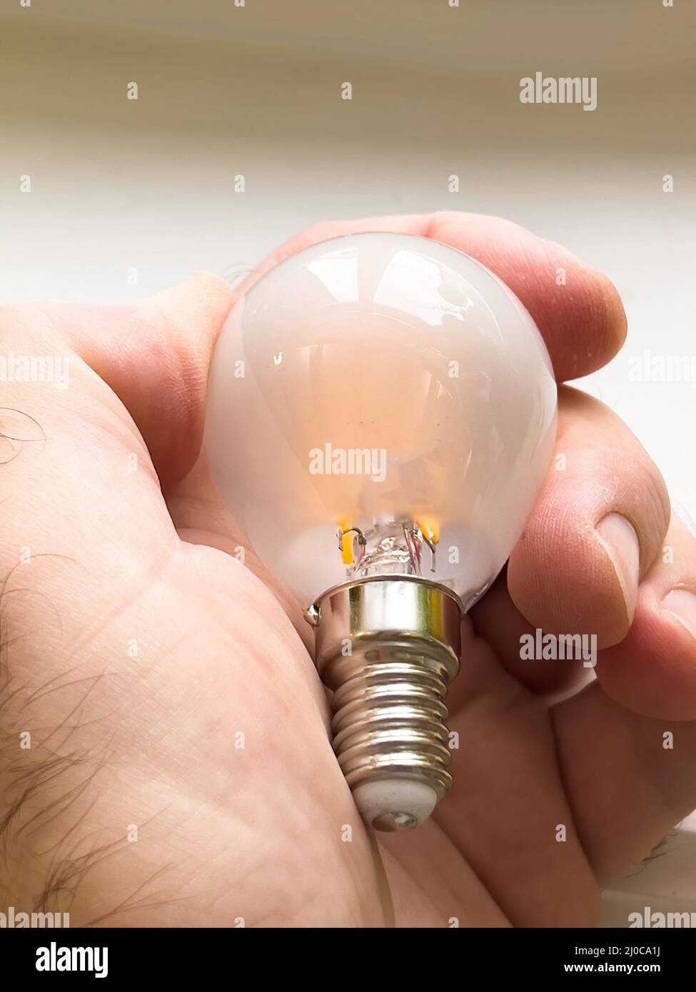POV male hand holding new LEd E14 socket bulb in hand Stock Photo - Alamy