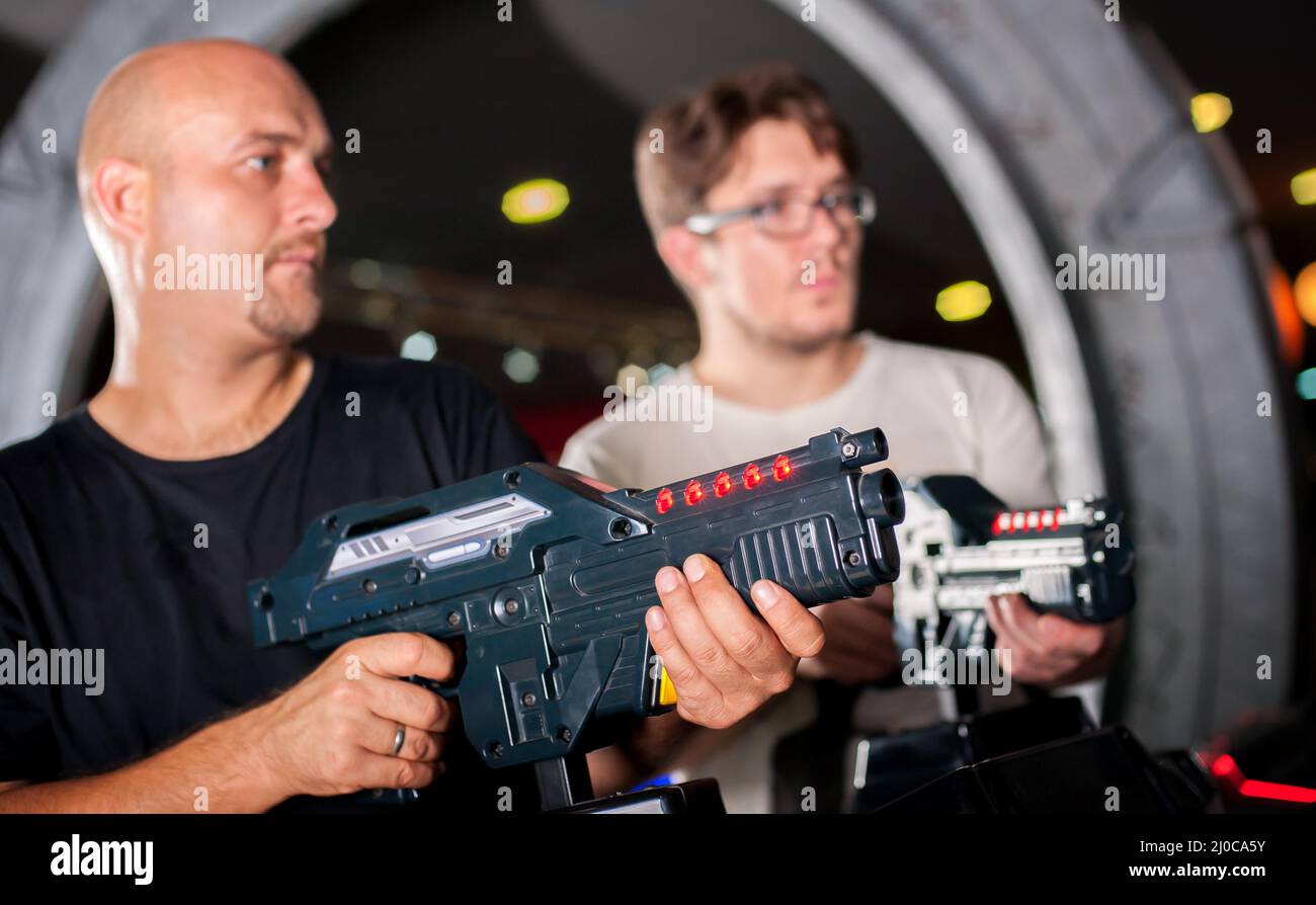 Friends playing with a toy shotgun on target in room Stock Photo - Alamy