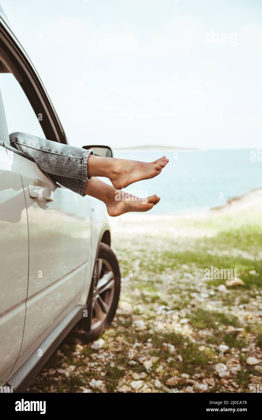 woman legs stick out from car window sea beach on background. summer ...