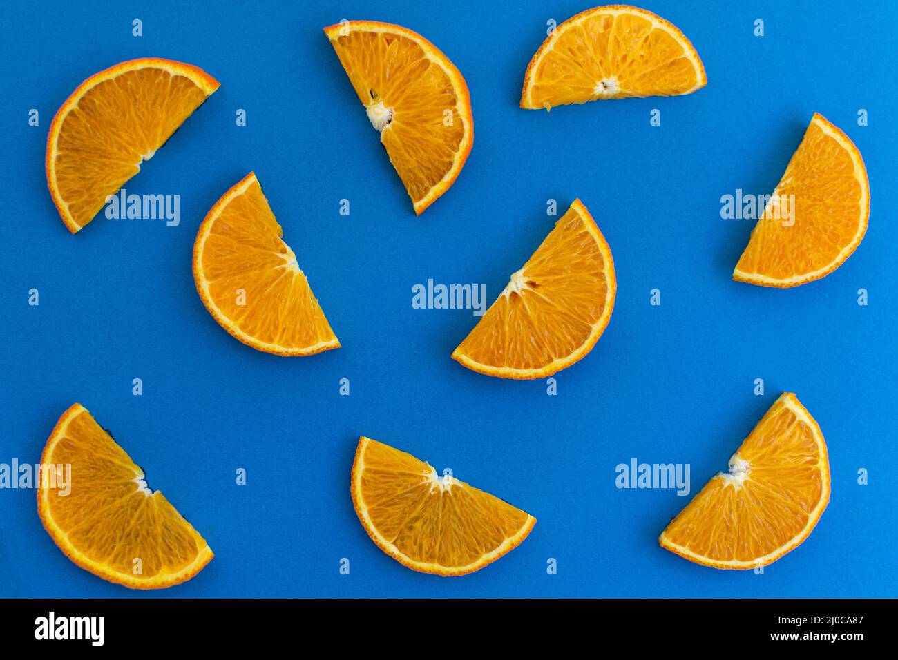 Orange slices cut in half on a blue background, complementary colors ...
