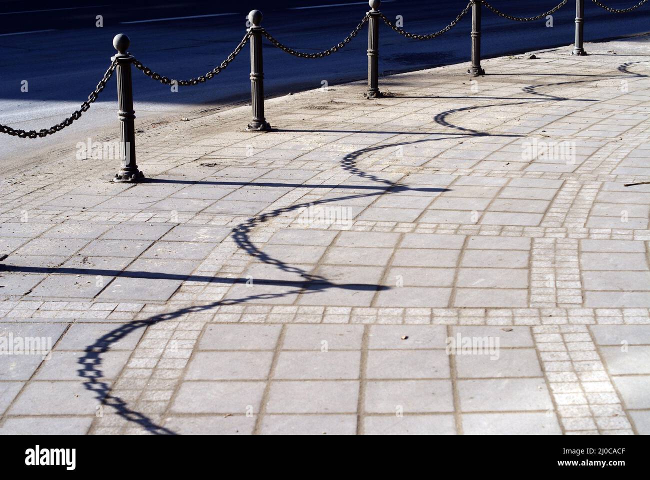 Closeup of metal poles connected with chins separating the road from ...