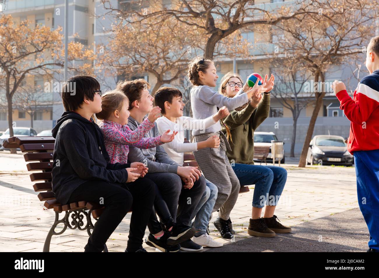 Children sitting on bench and playing ball Stock Photo - Alamy