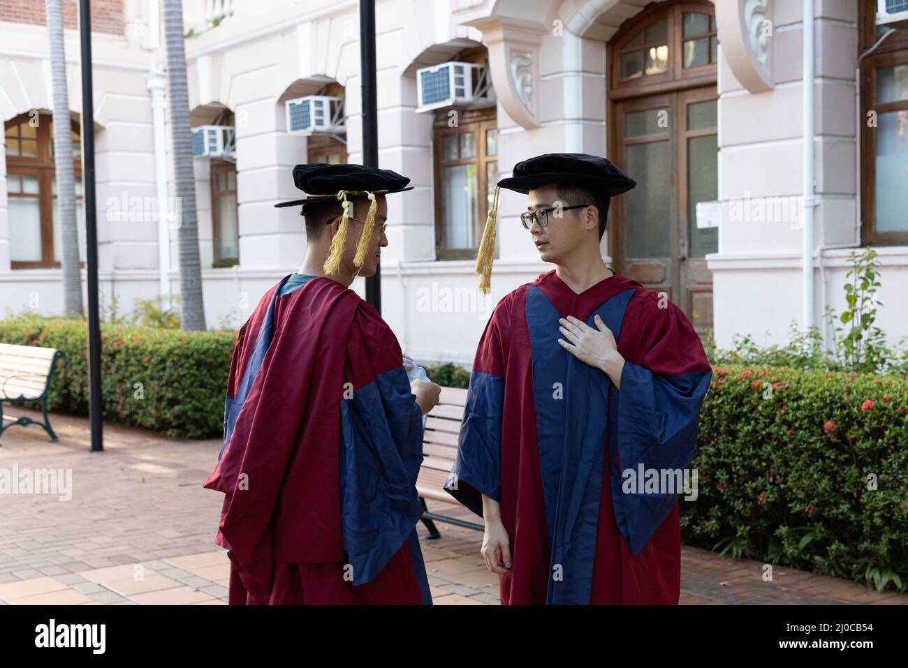 two happy proud PhD graduated male students in Academic dress gown ...