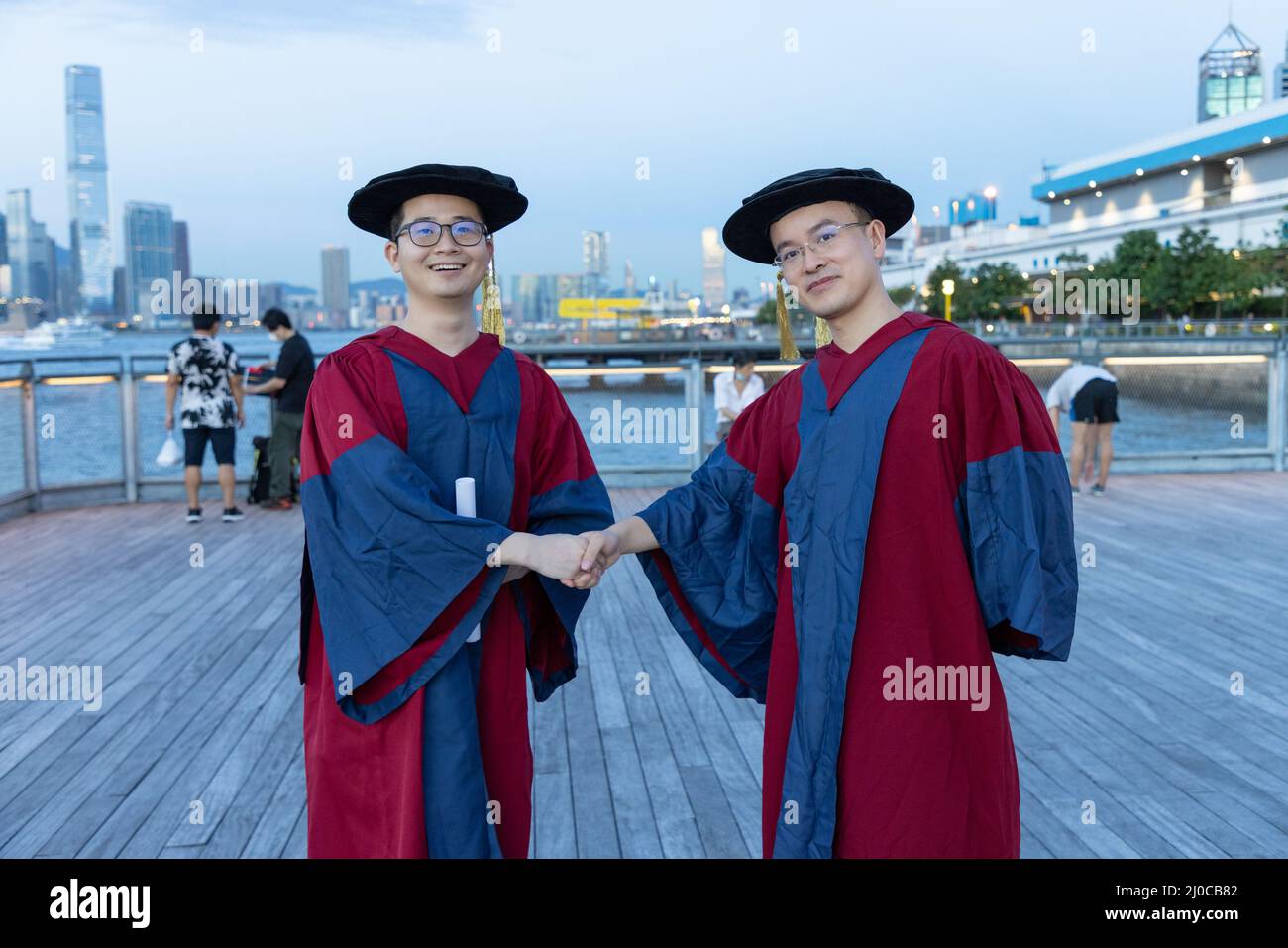 two happy proud PhD graduated male students in Academic dress gown ...