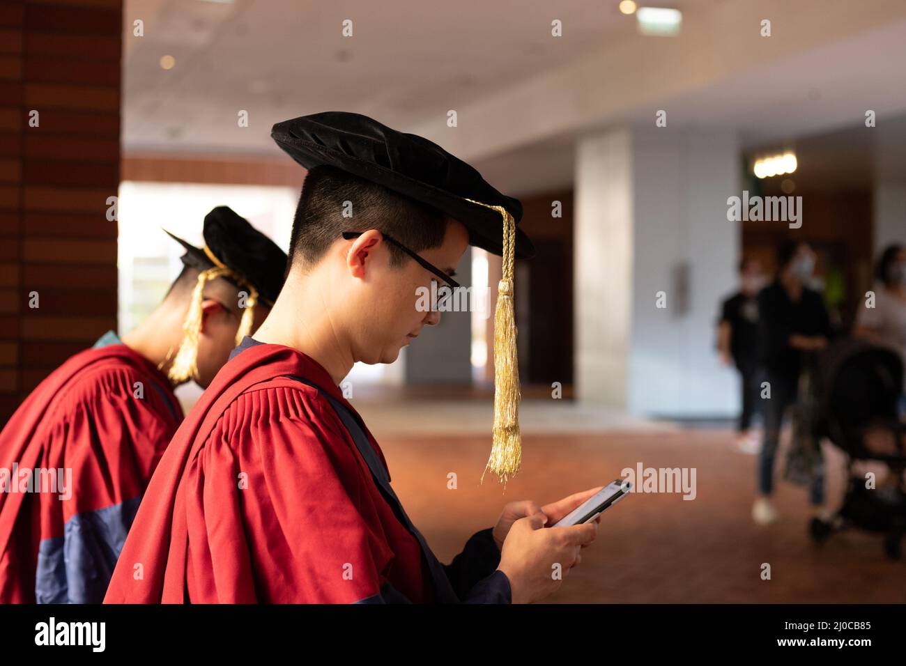 two happy proud PhD graduated male students in Academic dress gown read ...