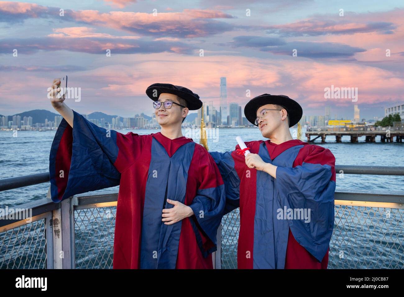 two happy proud PhD graduated male students in Academic dress gown ...