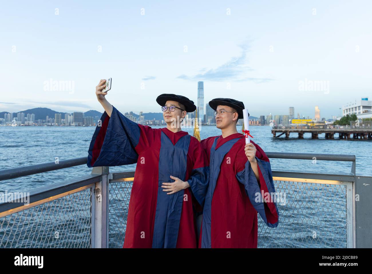 two happy proud PhD graduated male students in Academic dress gown ...