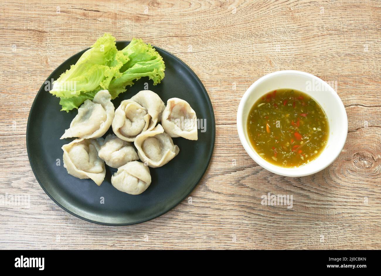 steamed fish dumpling with lettuce on plate dipping spicy and sour ...