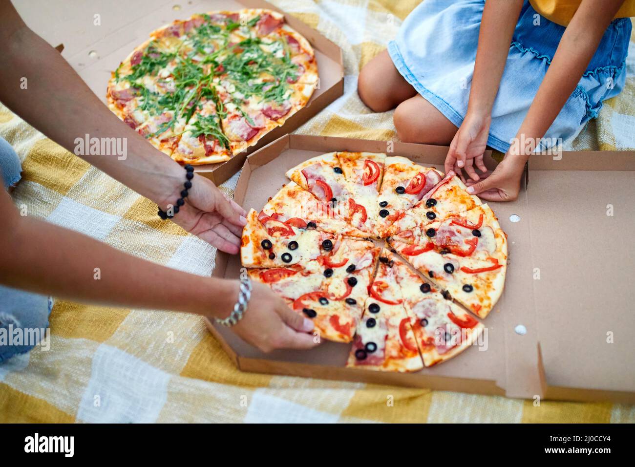 Sharing pizza, hands taking a piece of pizza from a box outdoor, family ...