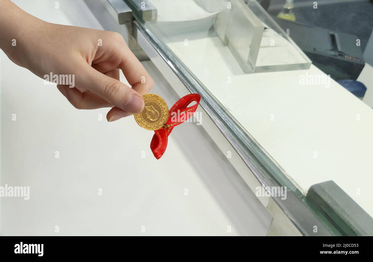 Hand holding a Turkish golden coin against a window Stock Photo - Alamy