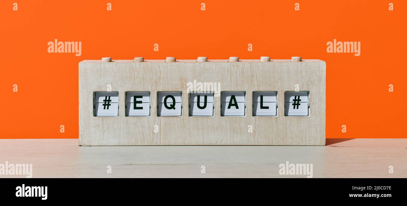 the word equal in a rustic wooden split flap board, on a wooden surface ...