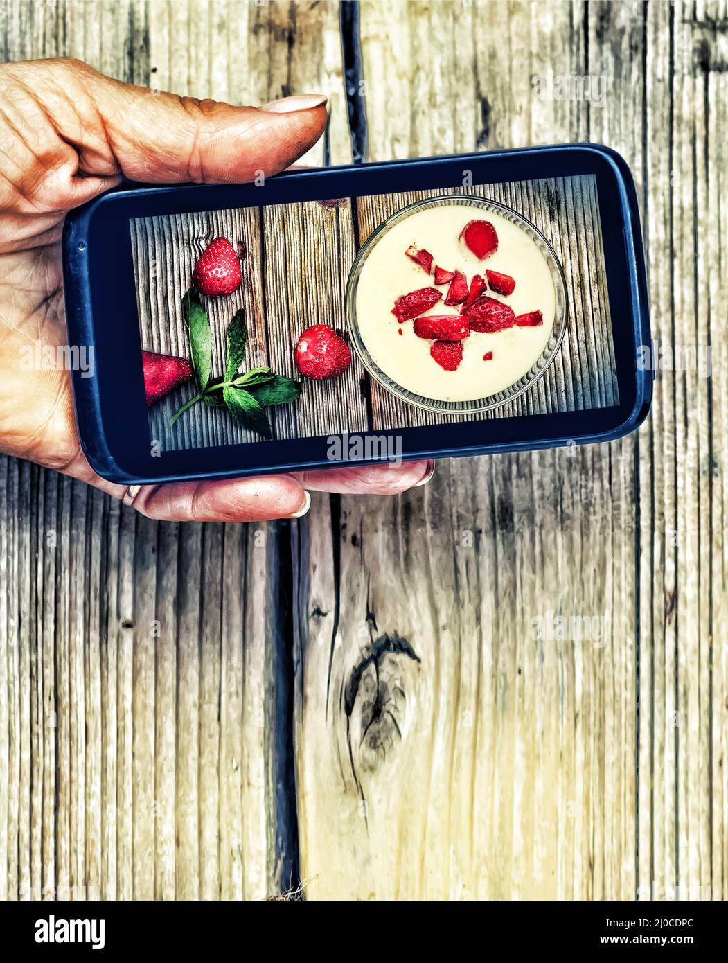 Smartphone in a female hand. display image of strawberry milkshake ...