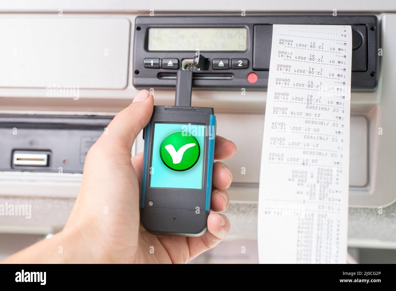 Driver holding a digital tachograph reader with a green OK check mark ...