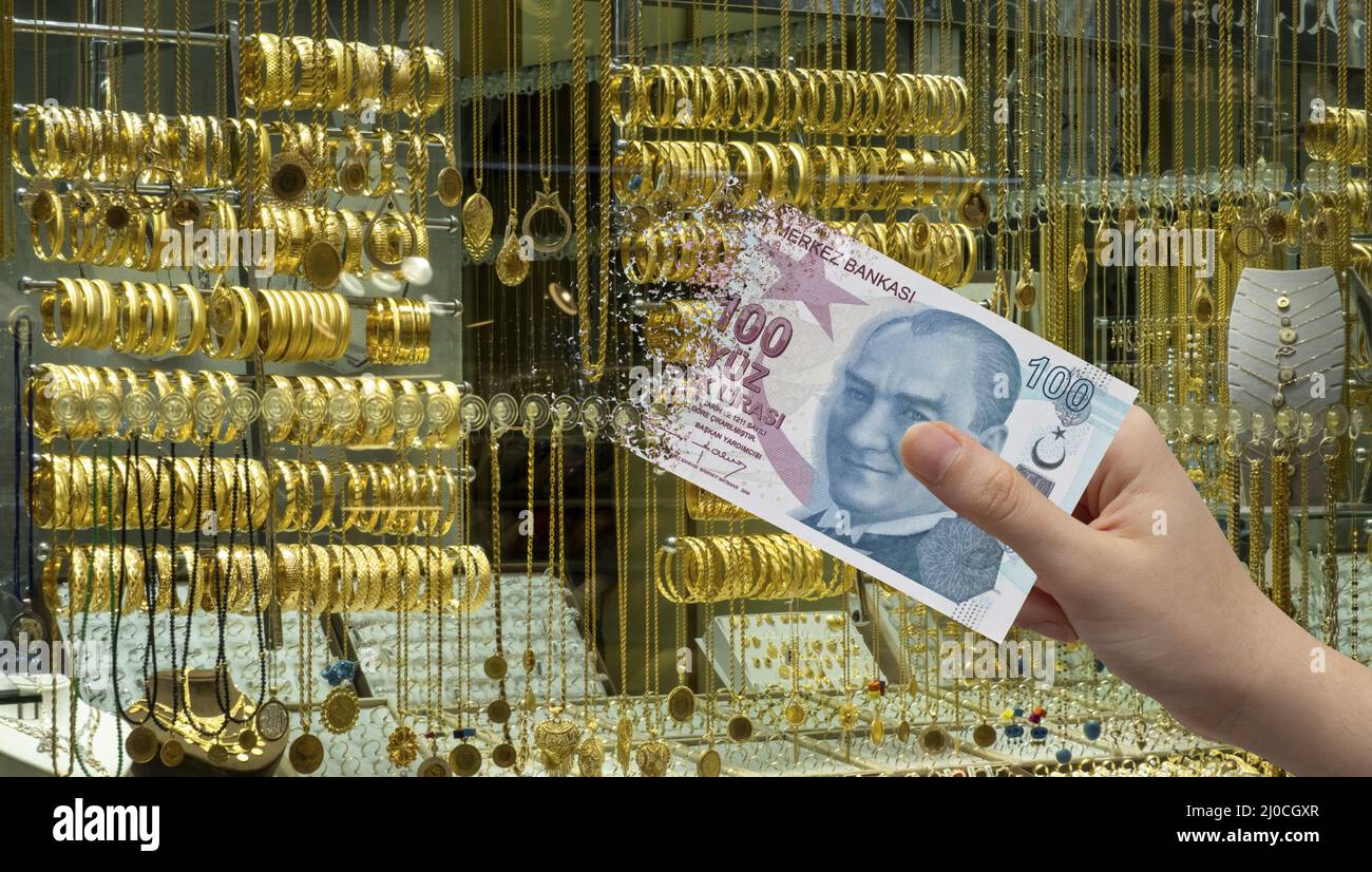 Hand holding the partially seen Turkish lira in front of the gold ...