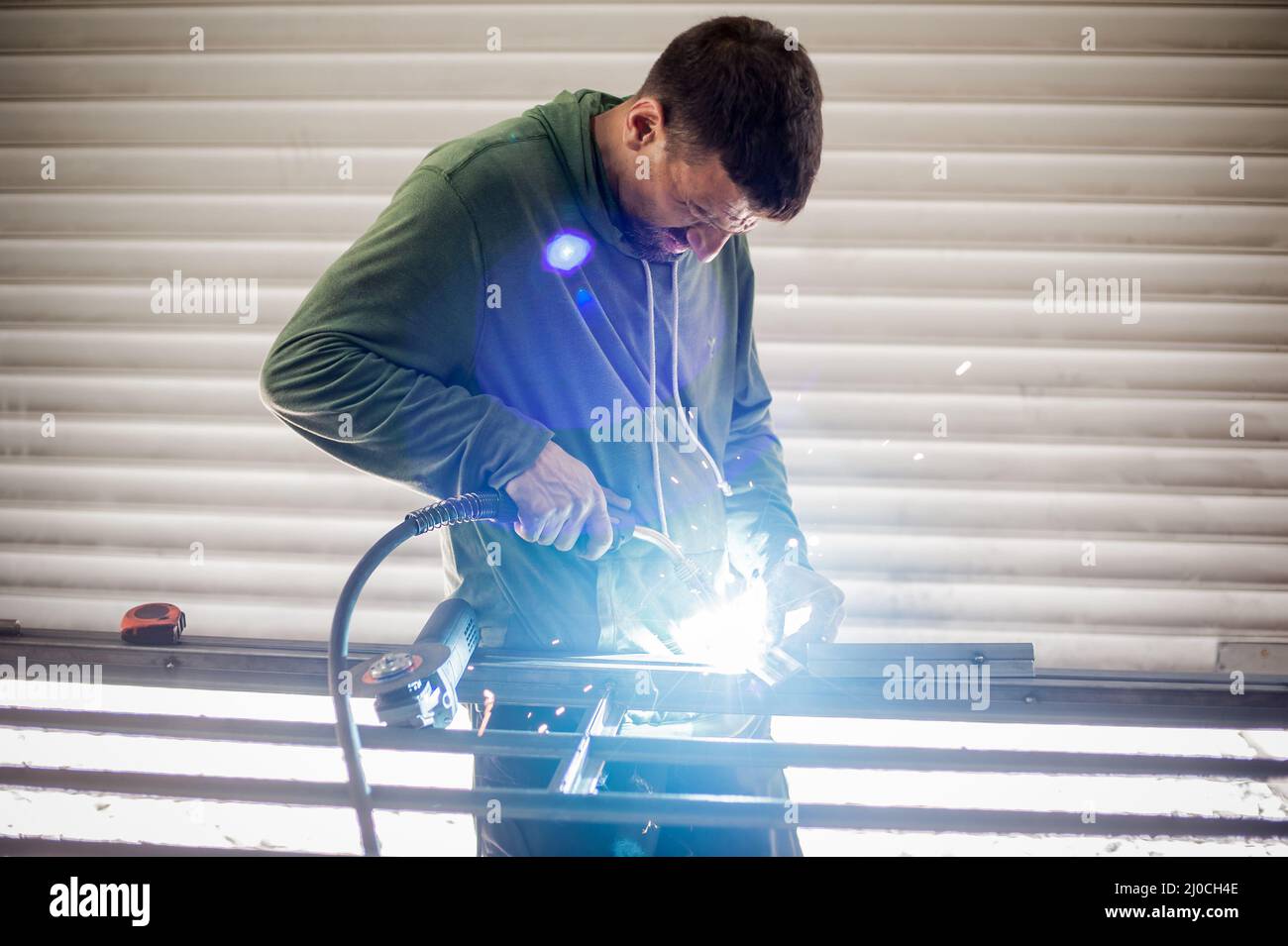 Industrial worker welding the steel structure in the workshop. Flies of ...