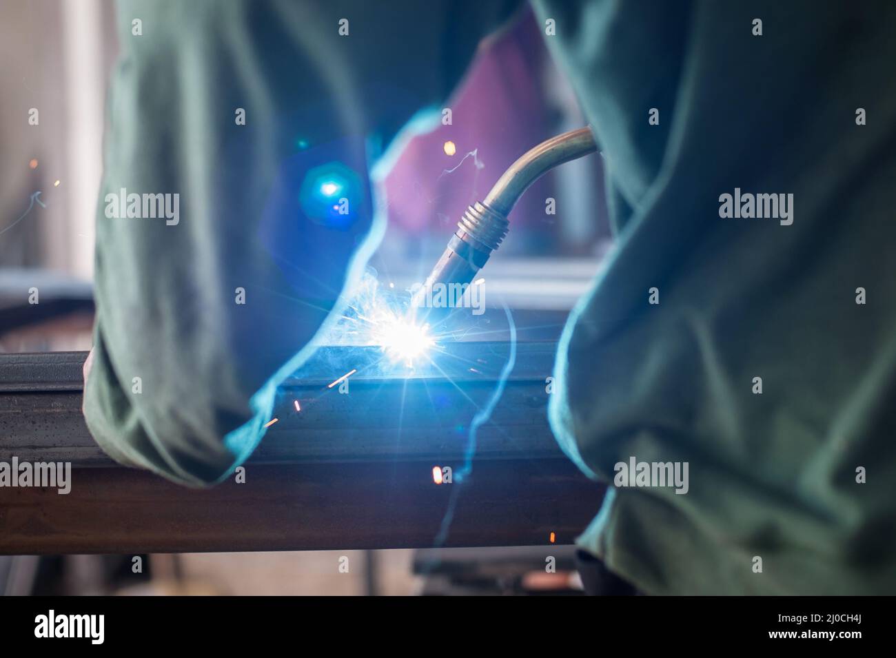 Industrial worker welding the steel structure in the workshop. Flies of ...