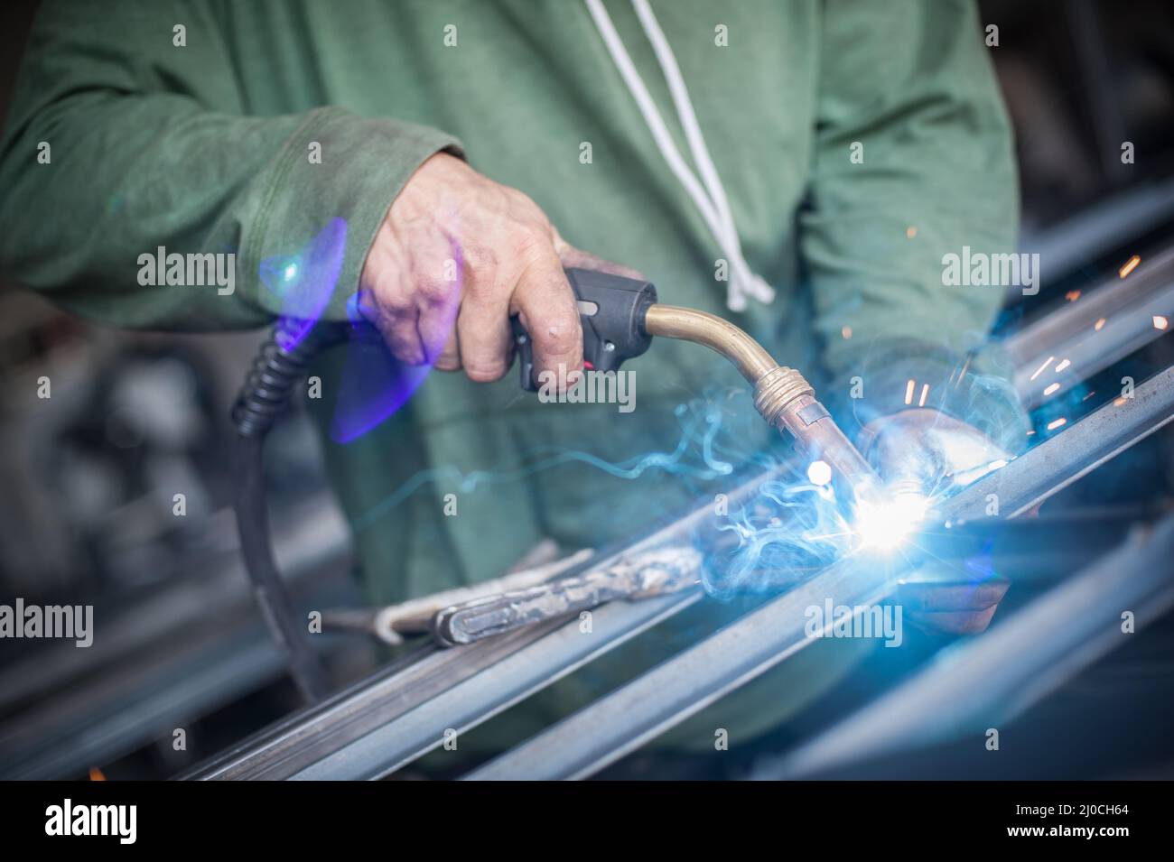 Industrial worker welding the steel structure in the workshop. Flies of ...