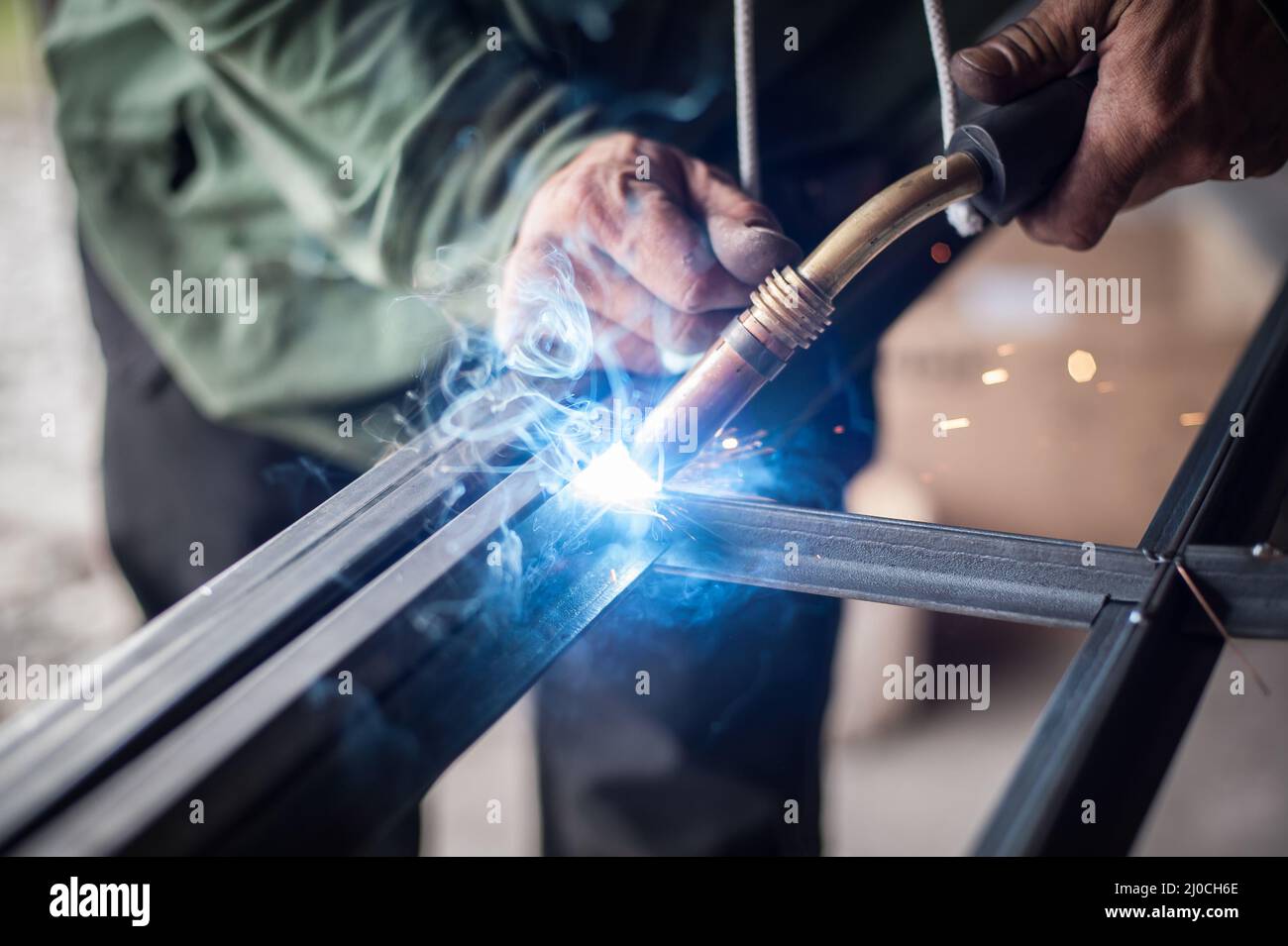 Industrial worker welding the steel structure in the workshop. Flies of ...