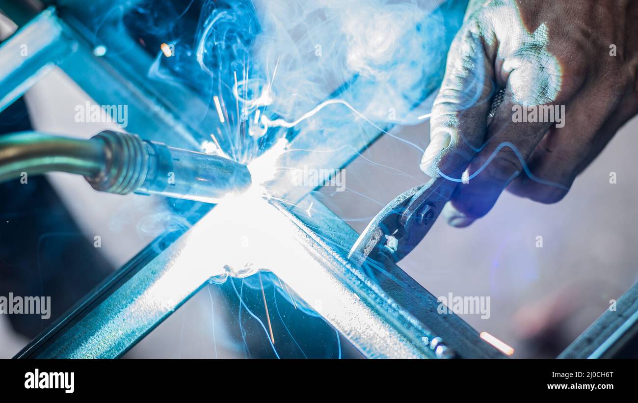 Industrial worker welding the steel structure in the workshop. Flies of ...