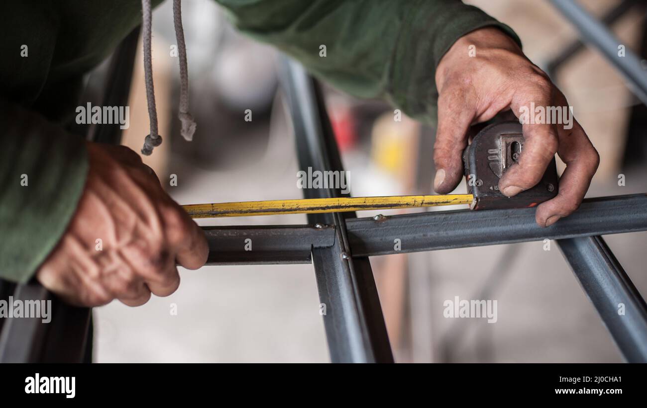 Worker measuring steel with measuring tape. Close up Stock Photo - Alamy