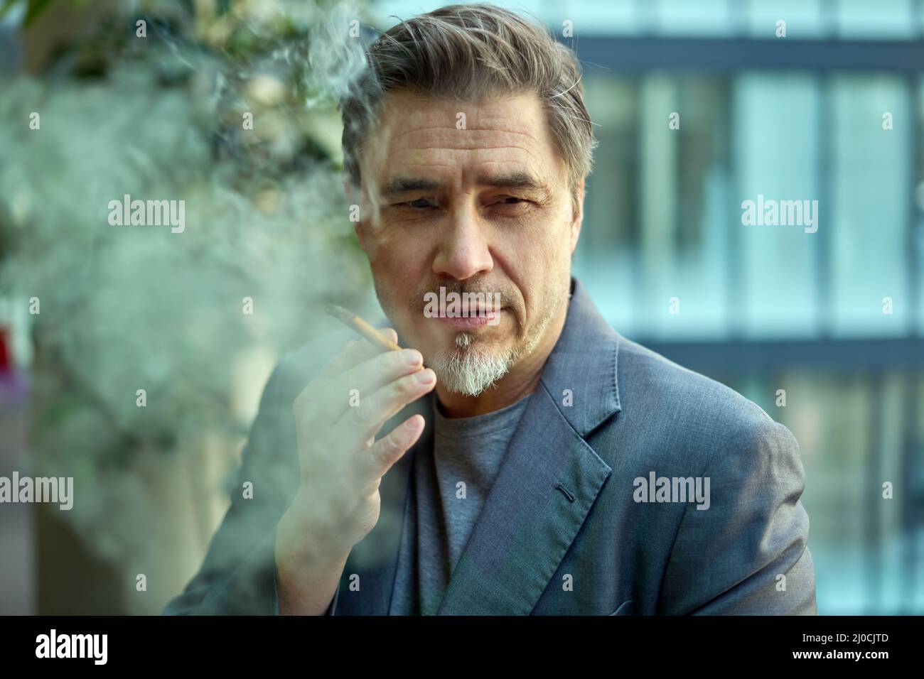 Middle age man smoking cigar outdoor in front of office building ...