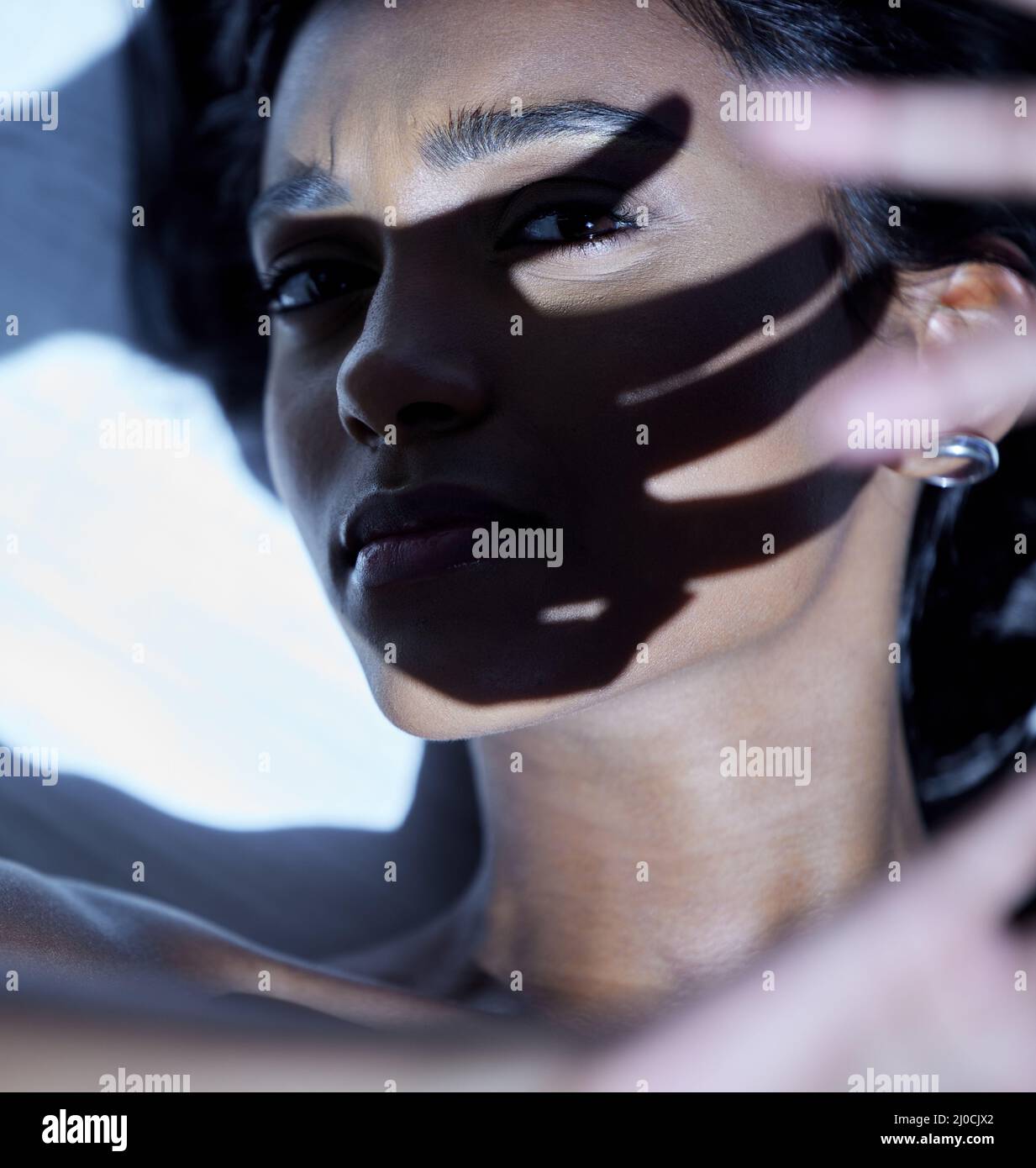 Im about to be blinded by this light. Shot of a young woman shielding ...