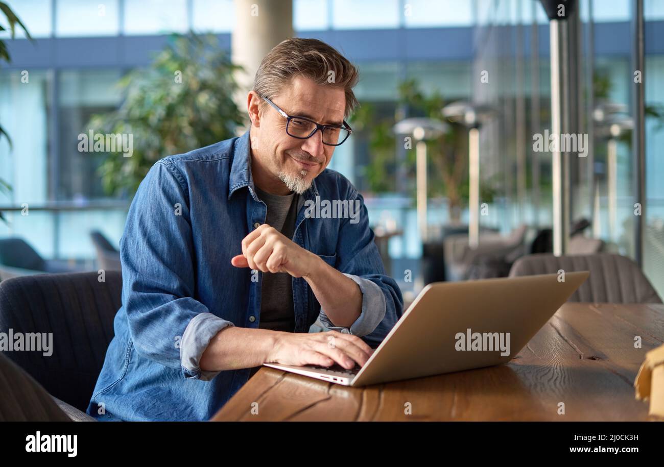 Happy middle age businessman using laptop computer in office. Older ...