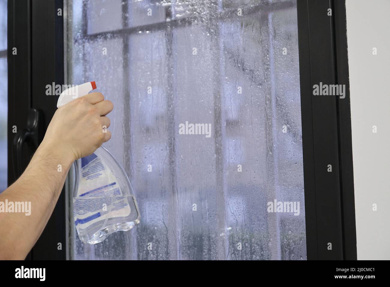 Man spraying window glass with water to install frosted window vinyl ...