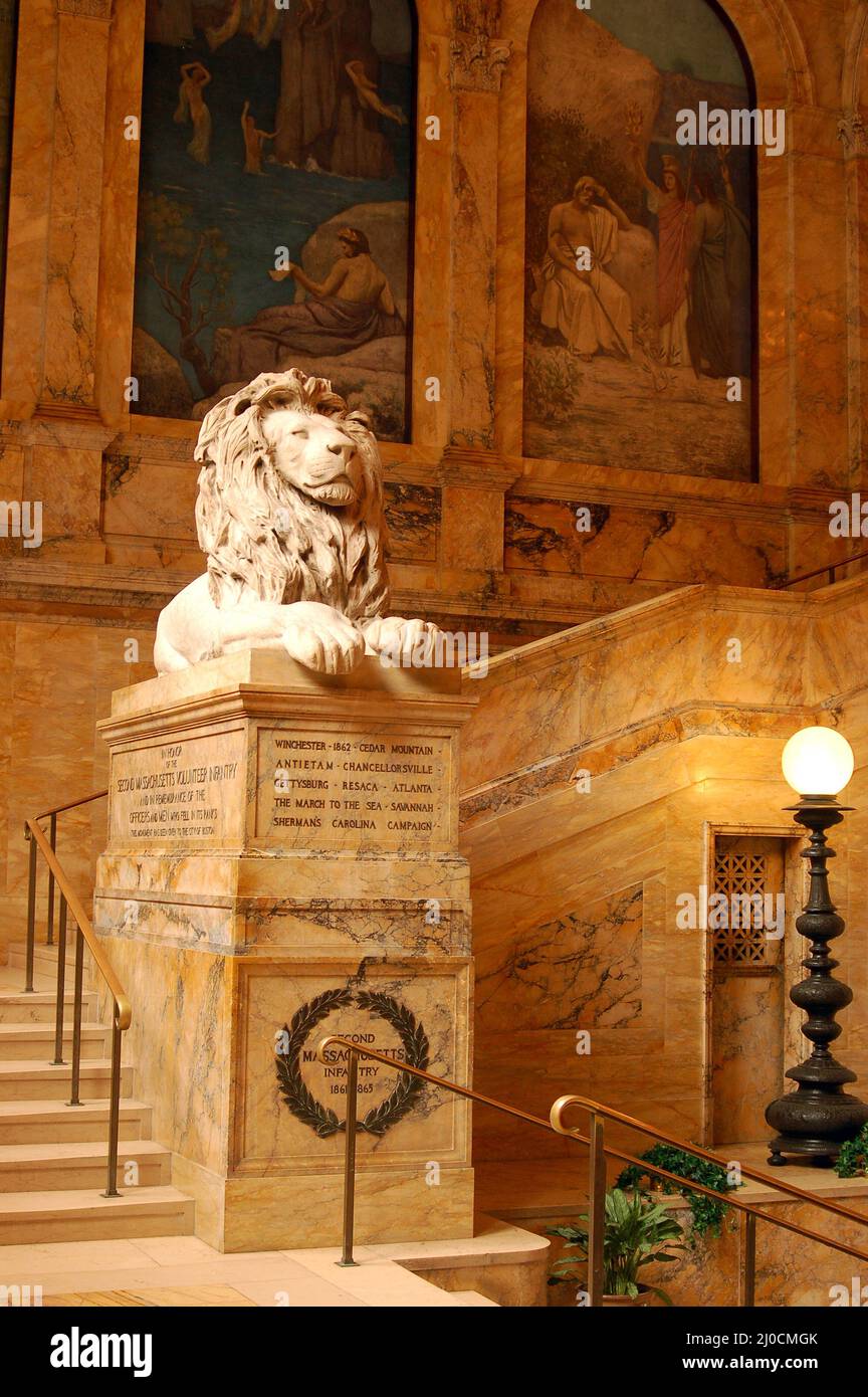 A lion lies on a marble pedestal in the main foyer of the Boston Public ...