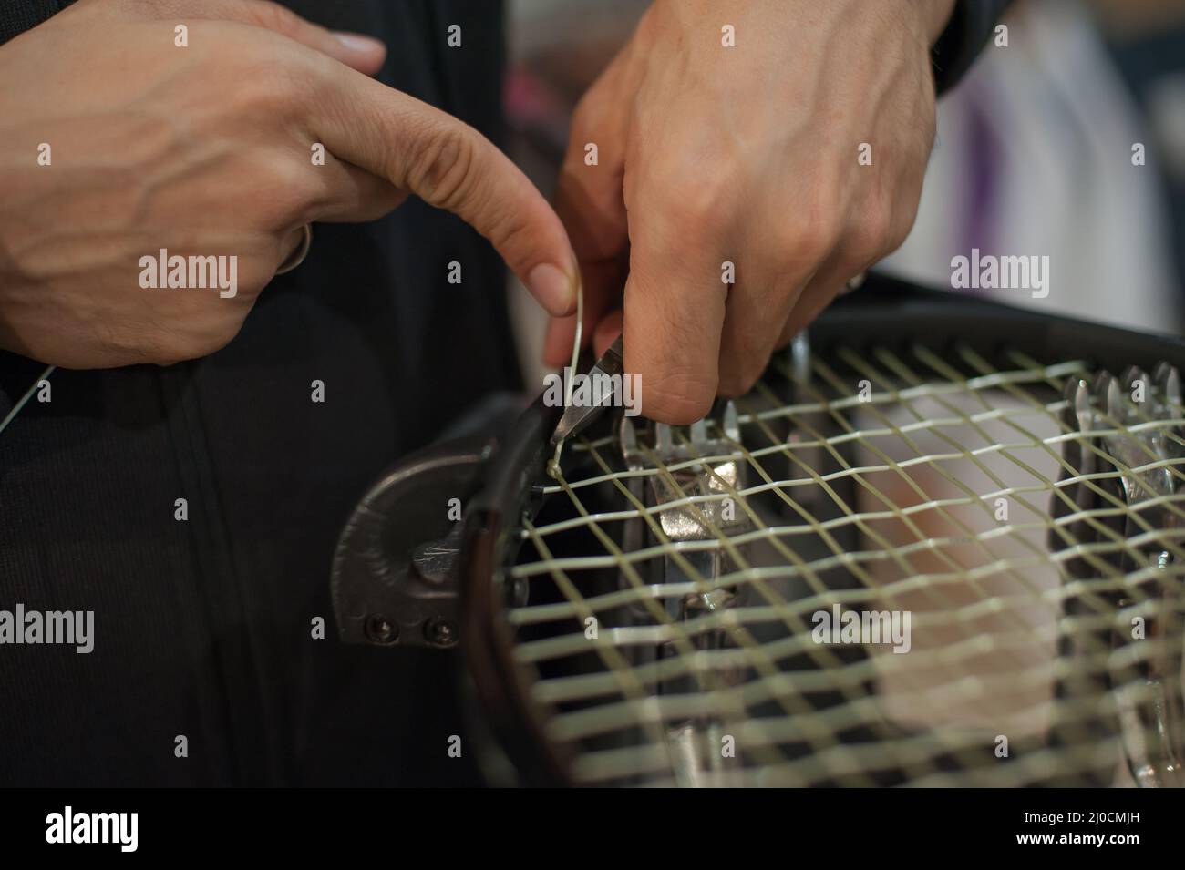 Stringing tennis racket. Tennis stringer tying knots and cutting string ...