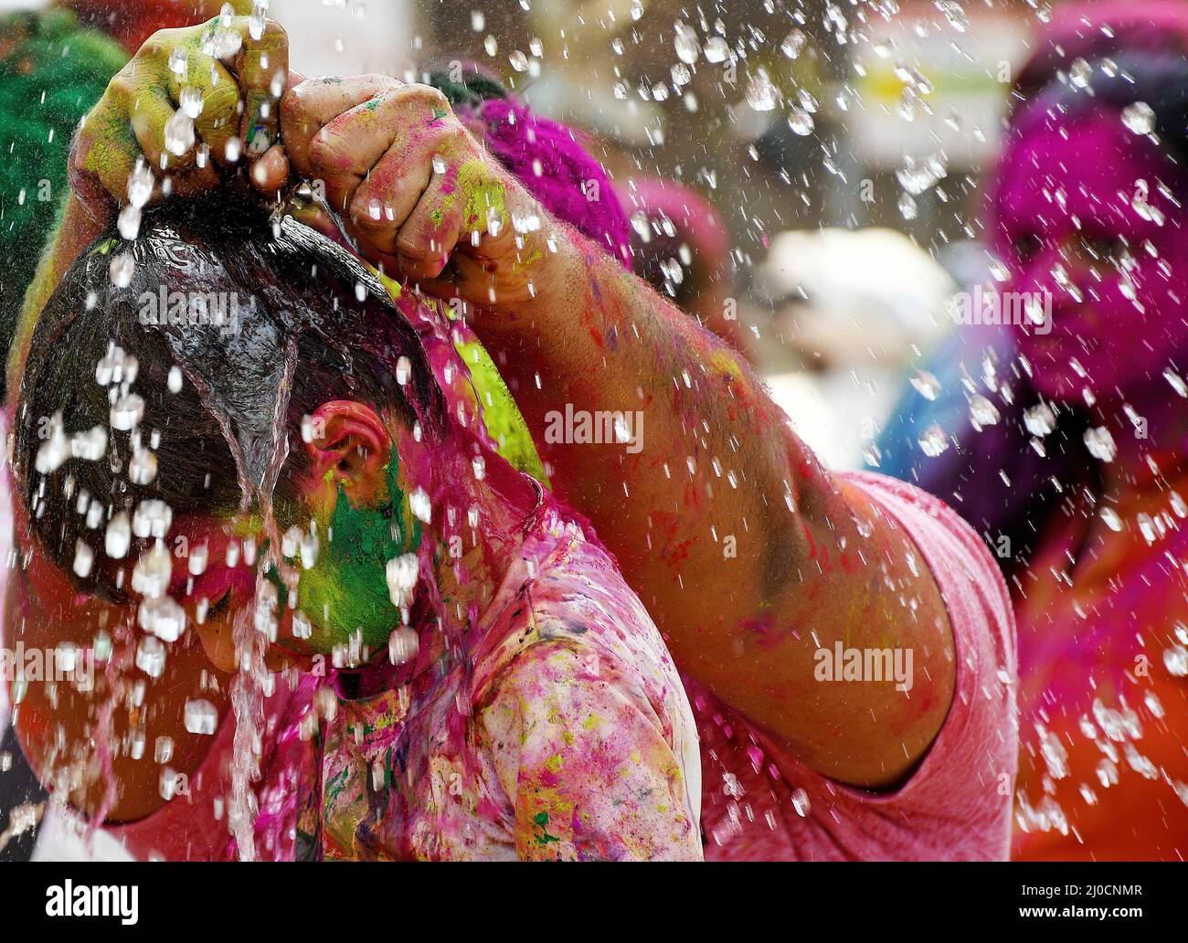 Mumbai, India. 18th Mar, 2022. A man bursts a water balloon on the head ...