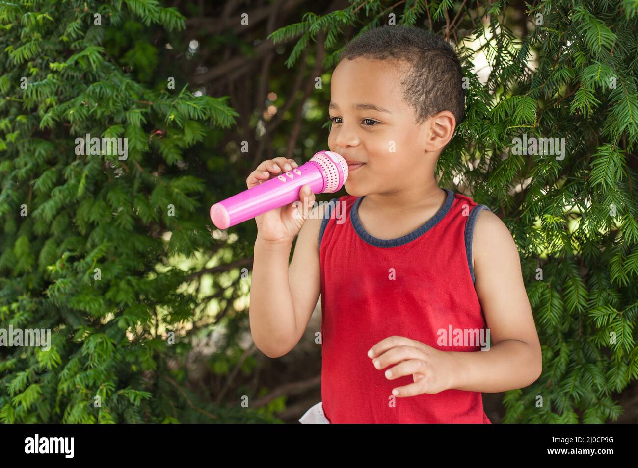 Cute little singer boy singing on the microphone in the city park ...