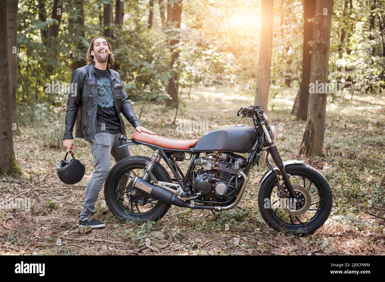 Handsome motorcyclist in black posing in front of his super sport ...
