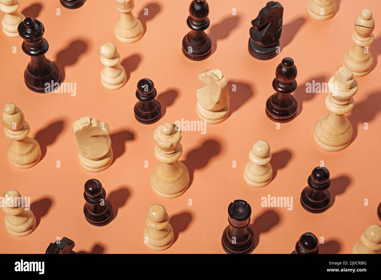 Assorted chess pieces arranged randomly on an orange background with ...