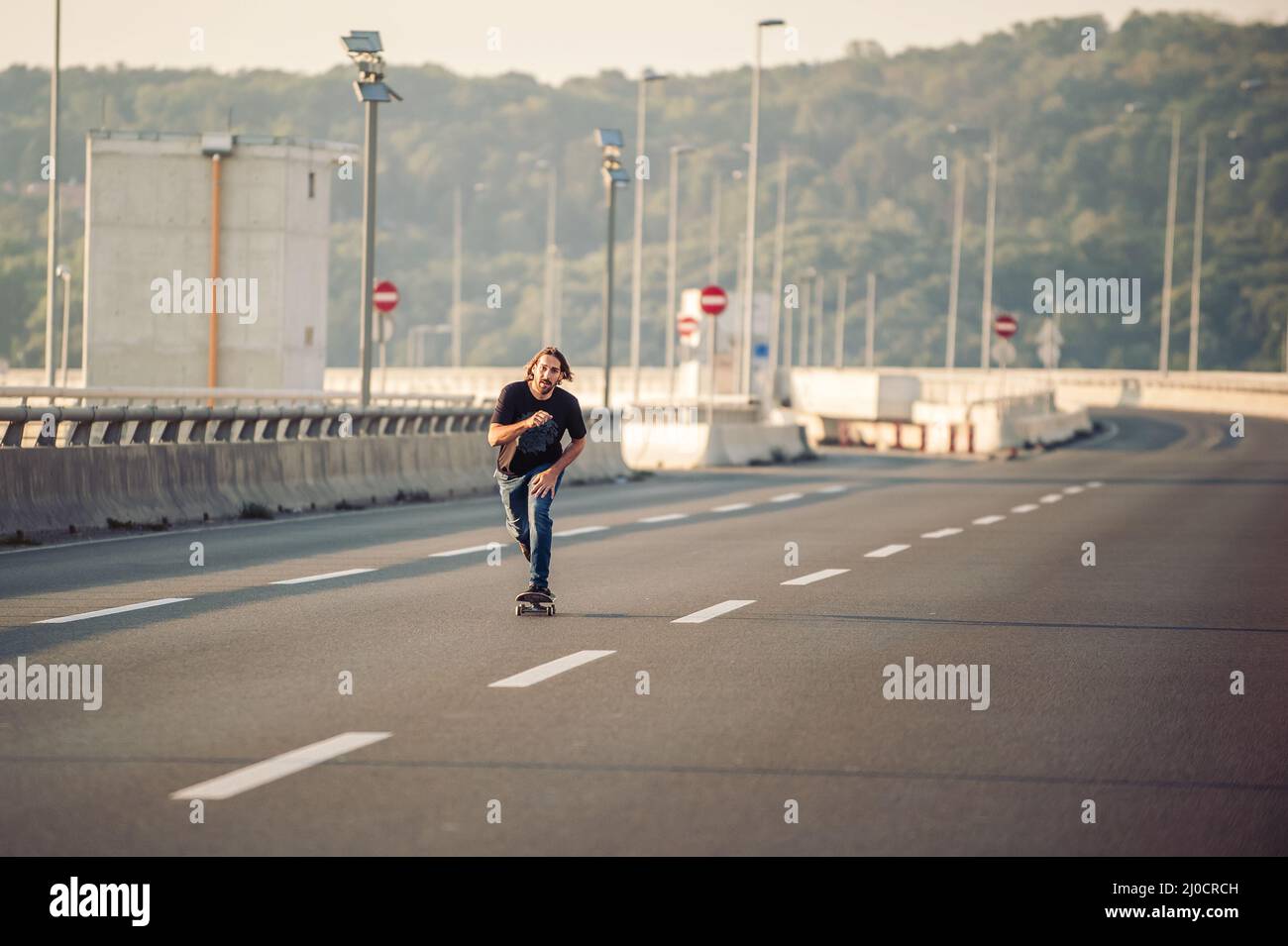 Professional skateboarder riding a skate over a city road bridge ...