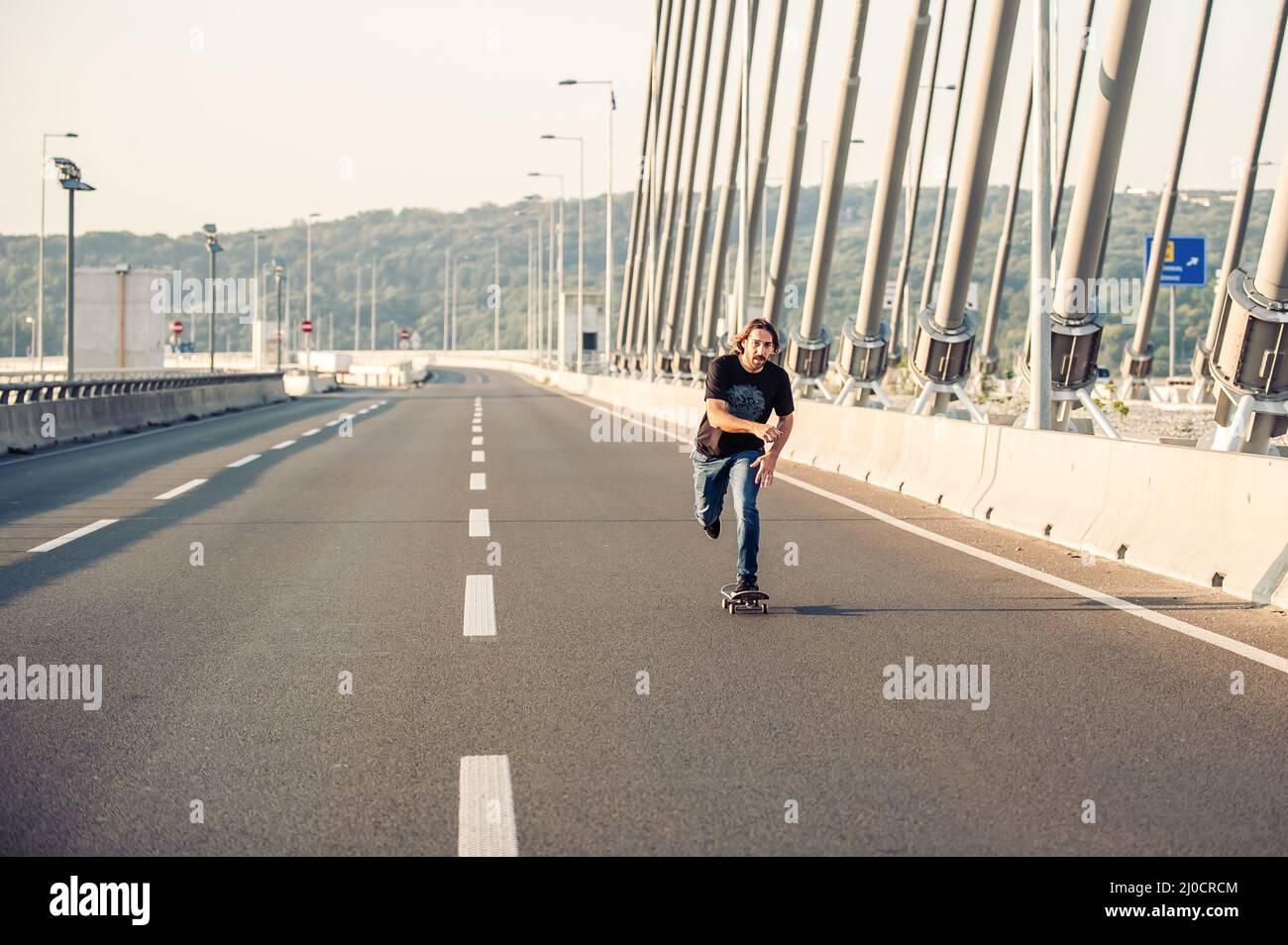 Professional skateboarder riding a skate over a city road bridge ...