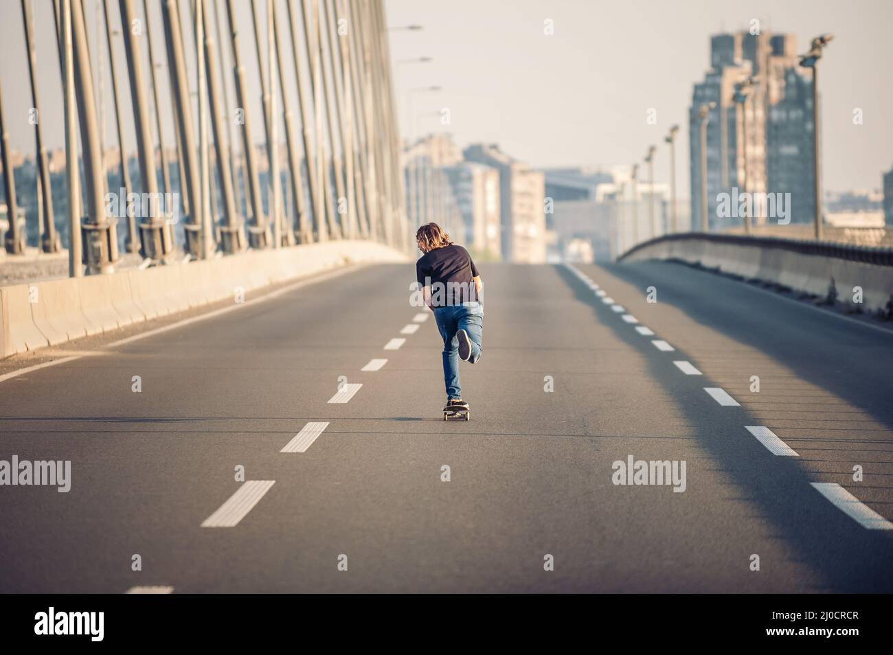 Professional skateboarder riding a skate over a city road bridge ...