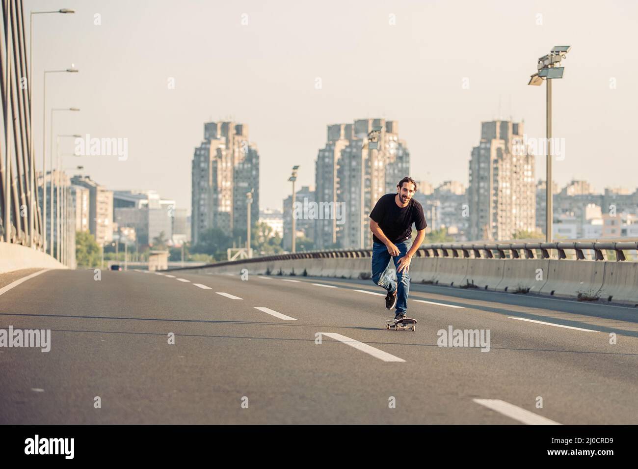 Professional skateboarder riding a skate over a city road bridge ...