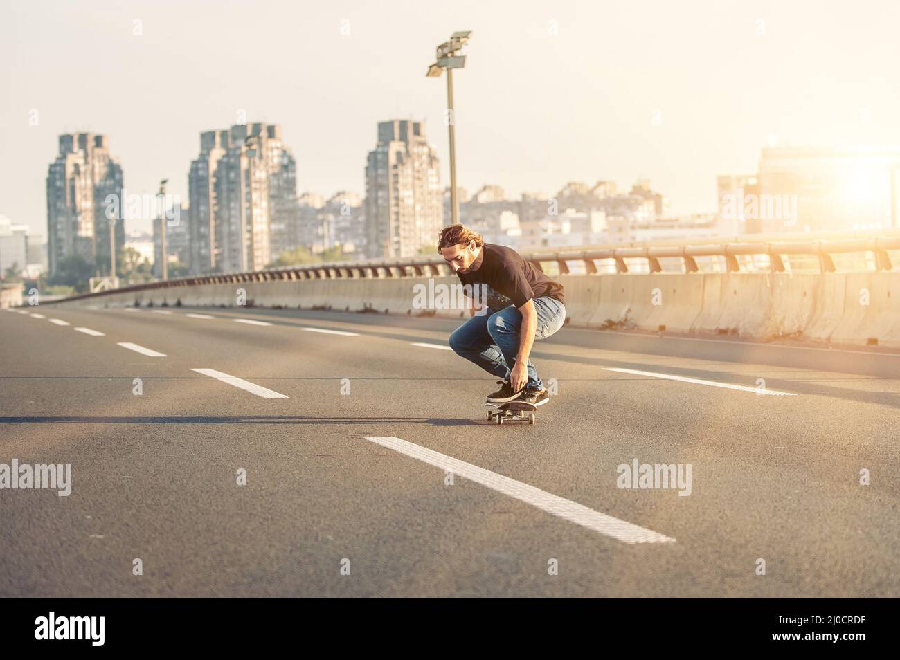 Professional skateboarder riding a skate over a city road bridge ...