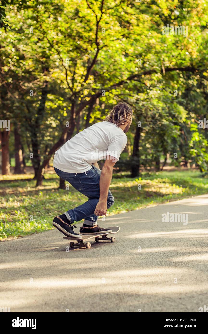 Skateboarder riding a skateboard slope on the road through the forest ...