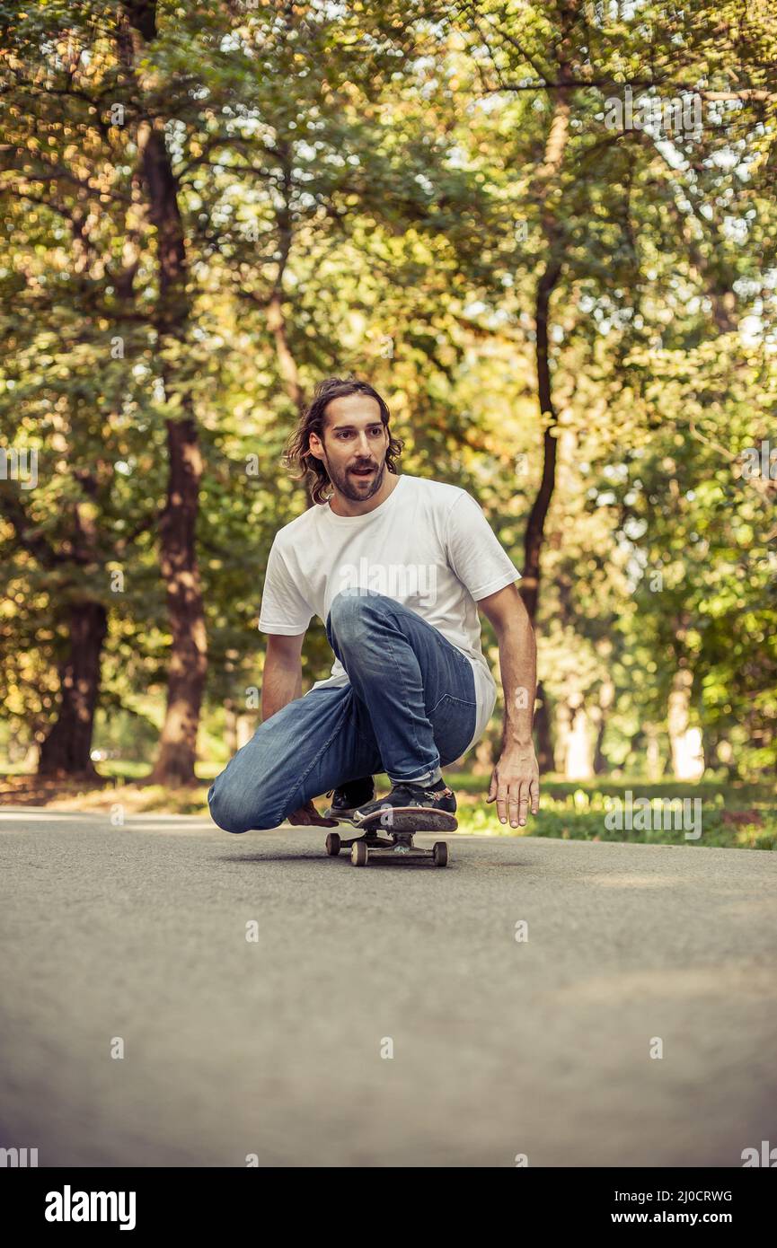 Skateboarder squatting on a skateboard and ride a slope on the road ...