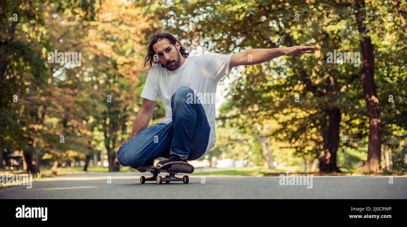 Skateboarder squatting on a skateboard and ride a slope on the road ...