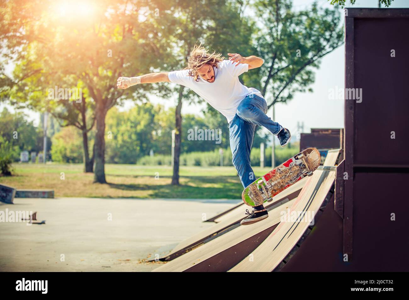 Young man doing skateboard trick on edge of skateboard park Stock Photo ...